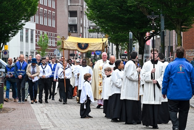 Winkelend publiek kijkt verbaasd naar religieuze stoet door Enschede ...
