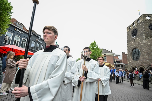 Winkelend publiek kijkt verbaasd naar religieuze stoet door Enschede ...